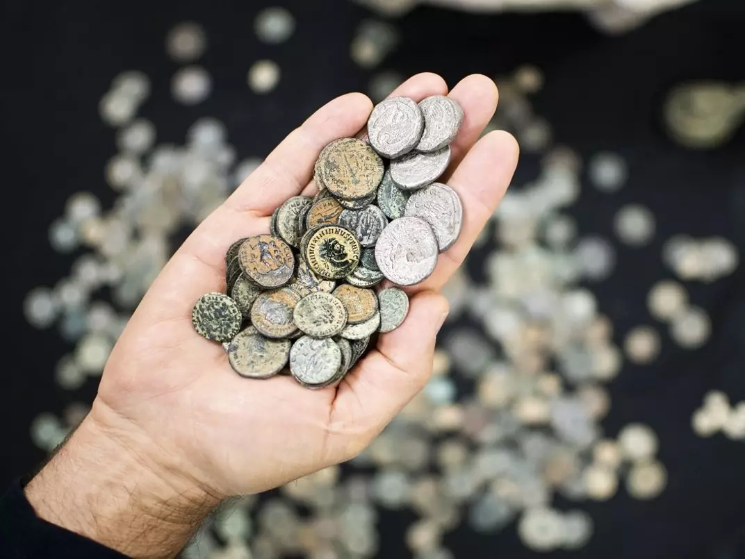 mão segurando um grande número de moedas antigas