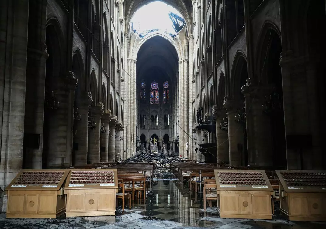 Et billede af katedralens indre i april 2019 viser affald, der dækker meget af jorden, mørk røg og andre skader fra branden